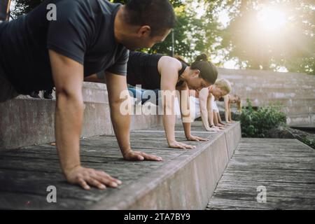 Woman practicing push-ups with fitness ball against gray background ...