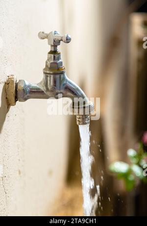 Open water tap in the backyard. Open faucet with water running. Waste ...