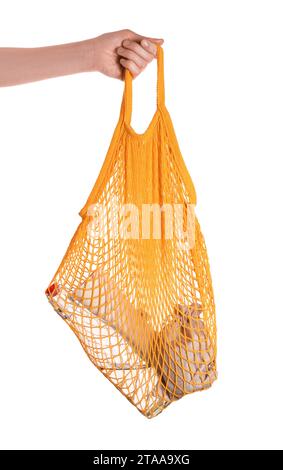 Woman holding net bag with different items on white background, closeup ...
