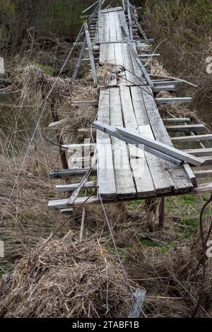 A broken pedestrian suspension bridge in the countryside after a spring ...
