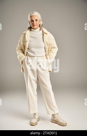 Middle age grey-haired woman doing yoga exercise sitting on table at ...