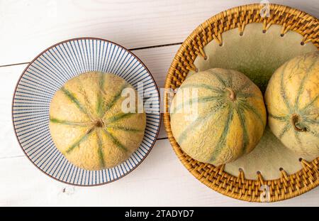 Three fragrant juicy, organic melons, close-up, on a straw mat, top ...