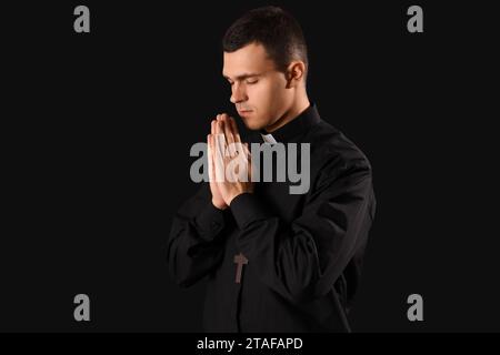 Young priest praying on dark background Stock Photo - Alamy