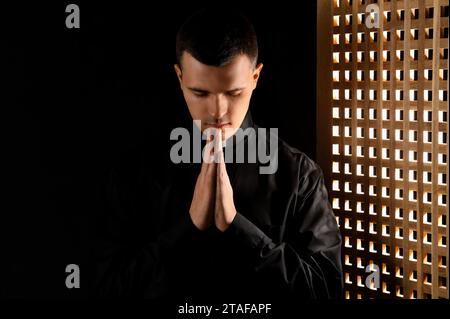 Young priest praying in confession booth, closeup Stock Photo - Alamy