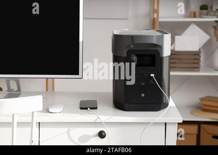 Comfortable workspace with modern computer and portable power station ...