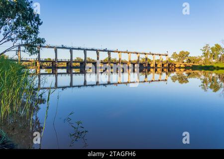 A row of flood gates along a weir across a wide calm river at St ...