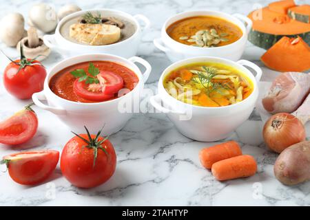 Tasty broth, different cream soups in bowls and ingredients on white ...