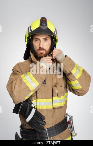 Strong, serious guy in fireman's uniform looking up and away in studio ...