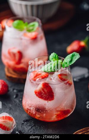 Two glasses of sweet strawberry frozen cocktails with mint garnish on a ...