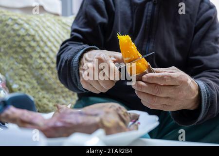Old man eating sweet potato Stock Photo - Alamy