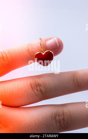 Red color heart shape earring in hand on white Stock Photo - Alamy
