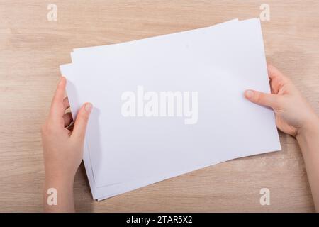 Hand holding sheets of paper on a wooden background Stock Photo - Alamy