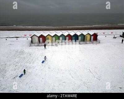 People walk through the snow beside the beach huts at Blyth in ...