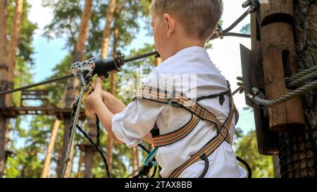 Little boy clamping safety rope hooks to the tree while climbing in ...