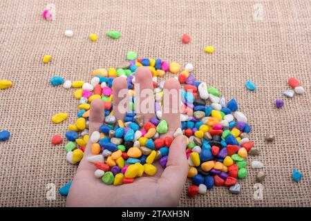 Colorful little pebbles in hand and on canvas ground Stock Photo - Alamy
