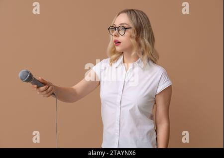 Portrait of shocked female journalist with microphone and clipboard ...