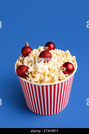 Bucket of popcorn with Christmas balls on red background with space for ...