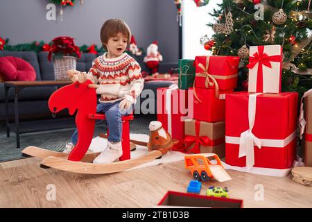Adorable toddler playing on rocking reindeer by christmas tree at home ...