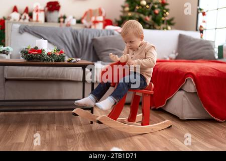 Adorable toddler playing on rocking reindeer by christmas tree at home ...