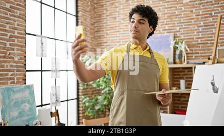 Young latin man artist smiling confident drawing on notebook at art ...