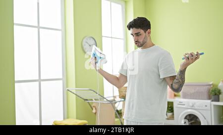 Young hispanic man with beard ironing clothes at home thinking ...