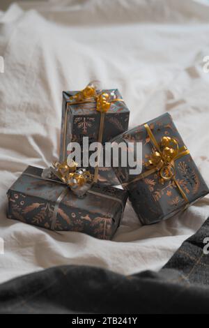 A gift wrapped in black and gold tree-pattern paper with a red bow ...