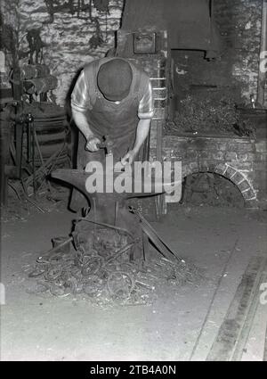 1970s, historical, inside a stone barn, a farrier shoeing a horse, with ...