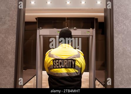 A security guard stationed with metal detectors at an office entrance ...
