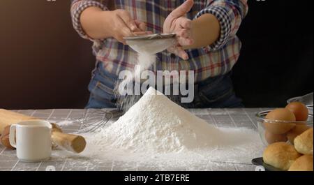 artisan bread working with dough. Use a sieve to sift flour into dough ...