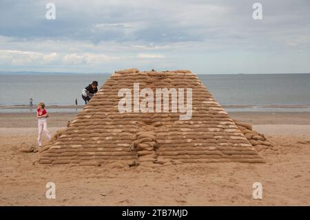 Art installation of sandbag pyramids on the beach Stock Photo - Alamy