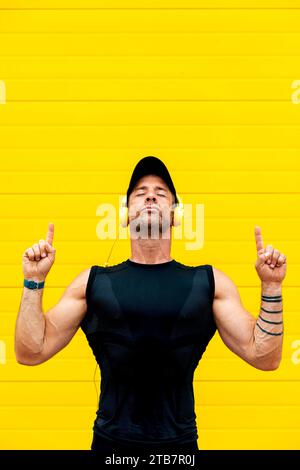 Sporty man listening music through earphones while exercising by river ...