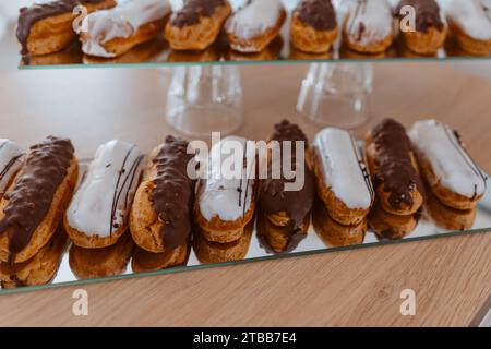 Eclairs with white and chocolate icing are laid out in a row on a ...