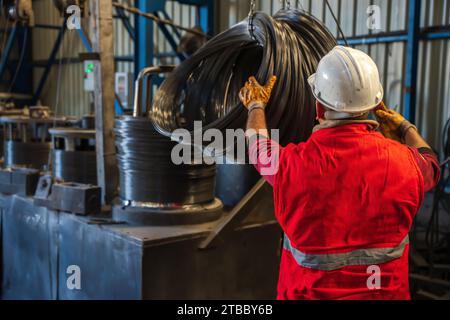Worker or man holding Coils of iron or steel wire stacked in the metal ...
