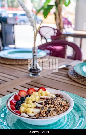 Pink bowl of fruit granola with fruits and honey, side view. Close-up ...