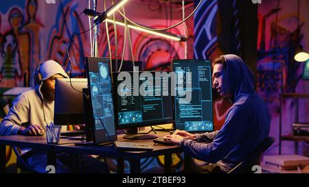 Asian hacker arriving in graffiti painted underground bunker, starting work on stealing valuable ...