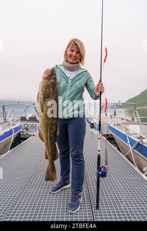 Happy Fisherwoman holding big arctic cod. Norway happy fishing. Woman ...