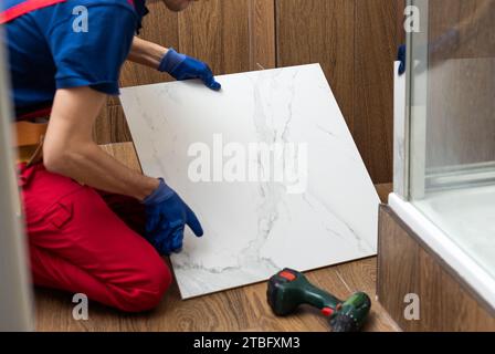 Master wearing work clothes checking vertical of installing tiles using ...