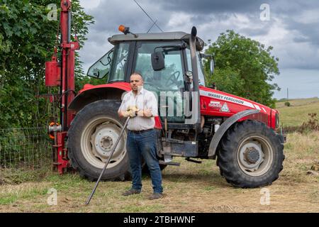 Fencing contrator with tools of his trade erecting a wire netting ...