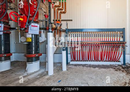 A rack of valves and red hoses in a small control room on the roof of a ...