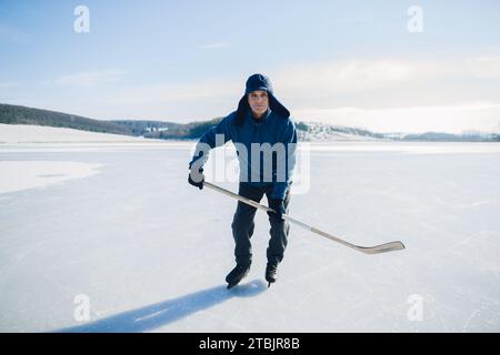 Senior man with hockey stick skating on ice in winter. Looking into the ...