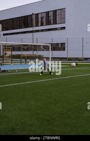Kid Goalkeeper catches the ball in stadium during a football game ...