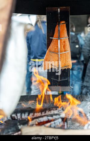 Smoked salmon fish fillet pinned on wooden plank board grilled on open ...