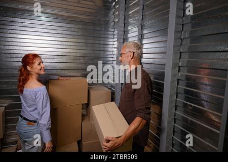Spouses loading cardboard boxes with things into a storage container ...