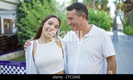 Confident father sharing sunny, joyful hug with smiling daughter at ...