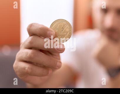 Handsome hispanic man holding litecoin cryptocurrency coin scared and ...