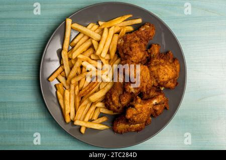 Baked chicken wings with French fries on brown plate Stock Photo - Alamy