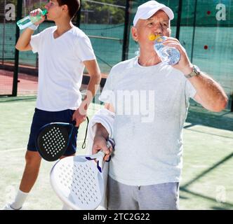 padel players of different generations drink water on padel court Stock ...