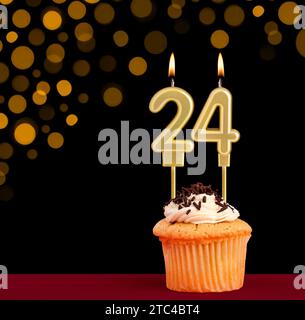 Chocolate cupcake with number 24 candle - Birthday on a yellow ...