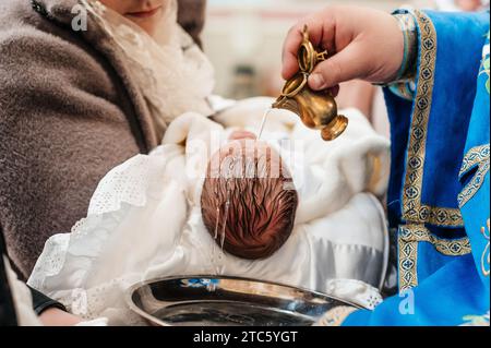 A priest pours water on the head of a small child during the Christian ...