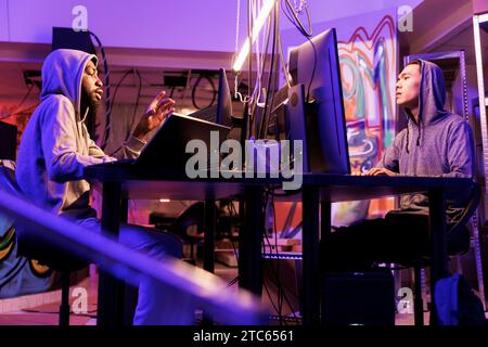 Men in hood discussing hacking plan with cheerful smile in abandoned ...